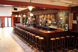 Uma área de bar com um balcão comprido, banquetes e um quadro de cardápio.