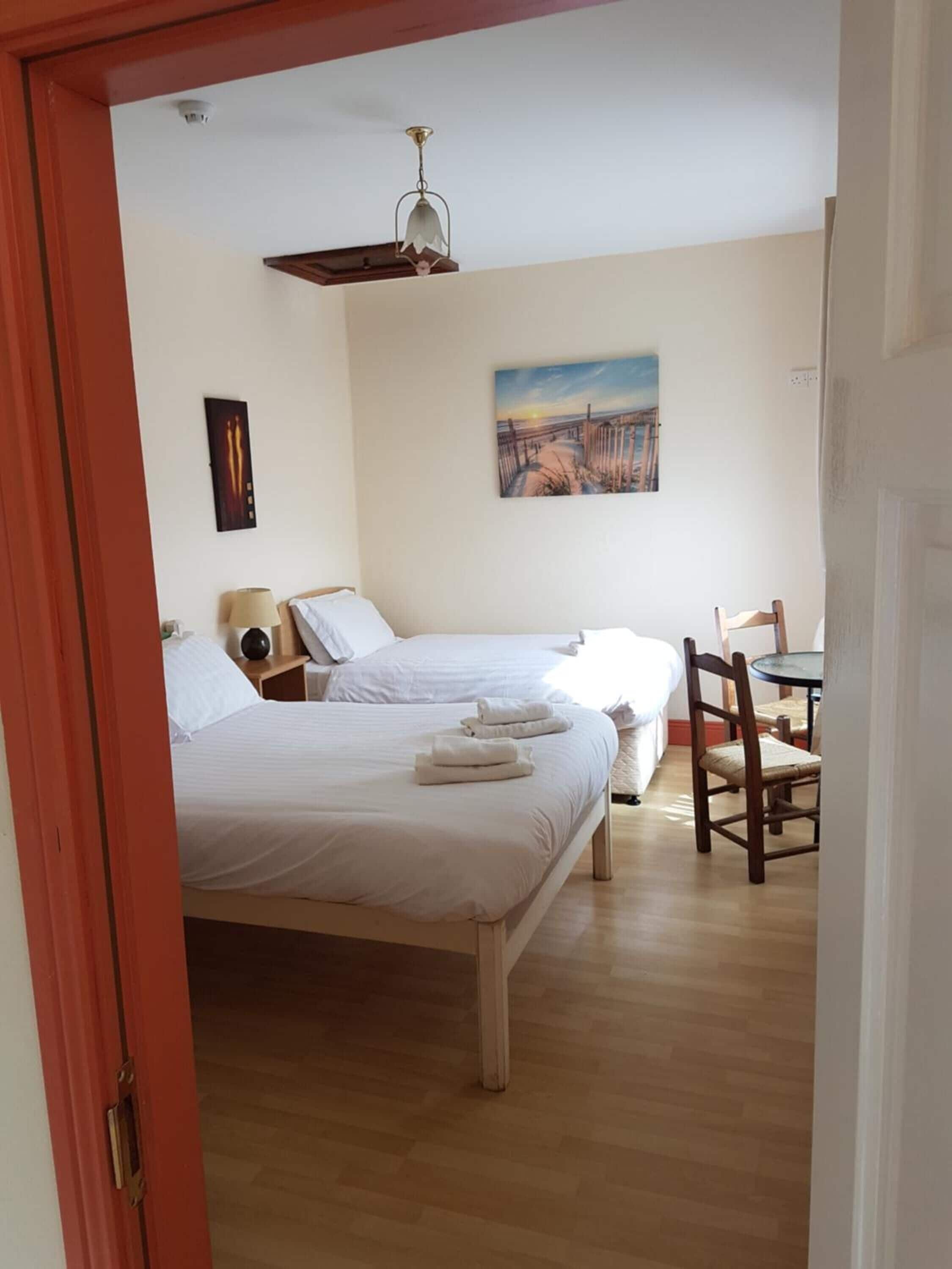 Quarto com duas camas, um quadro, uma lâmpada e uma cadeira.