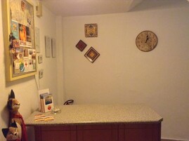 Um quarto com bancada de cozinha, relógio na parede e diversos objetos decorativos.