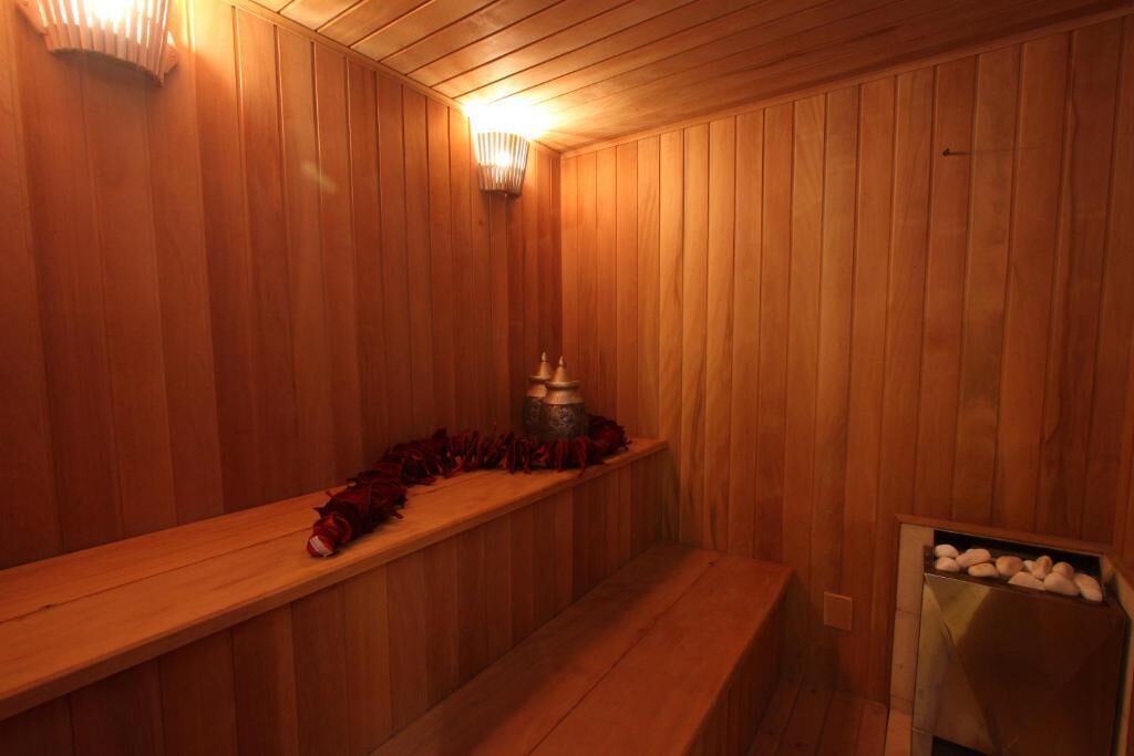 Uma sala de sauna de madeira com bancos e um banco com um objeto decorativo.