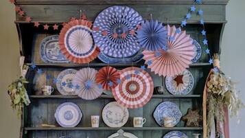 Uma prateleira de madeira com diversos objetos decorativos, incluindo leques de papel, pratos e um abajur de estilo vintage.