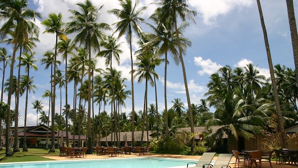 Uma área de piscina com espreguiçadeiras e um edifício ao fundo.