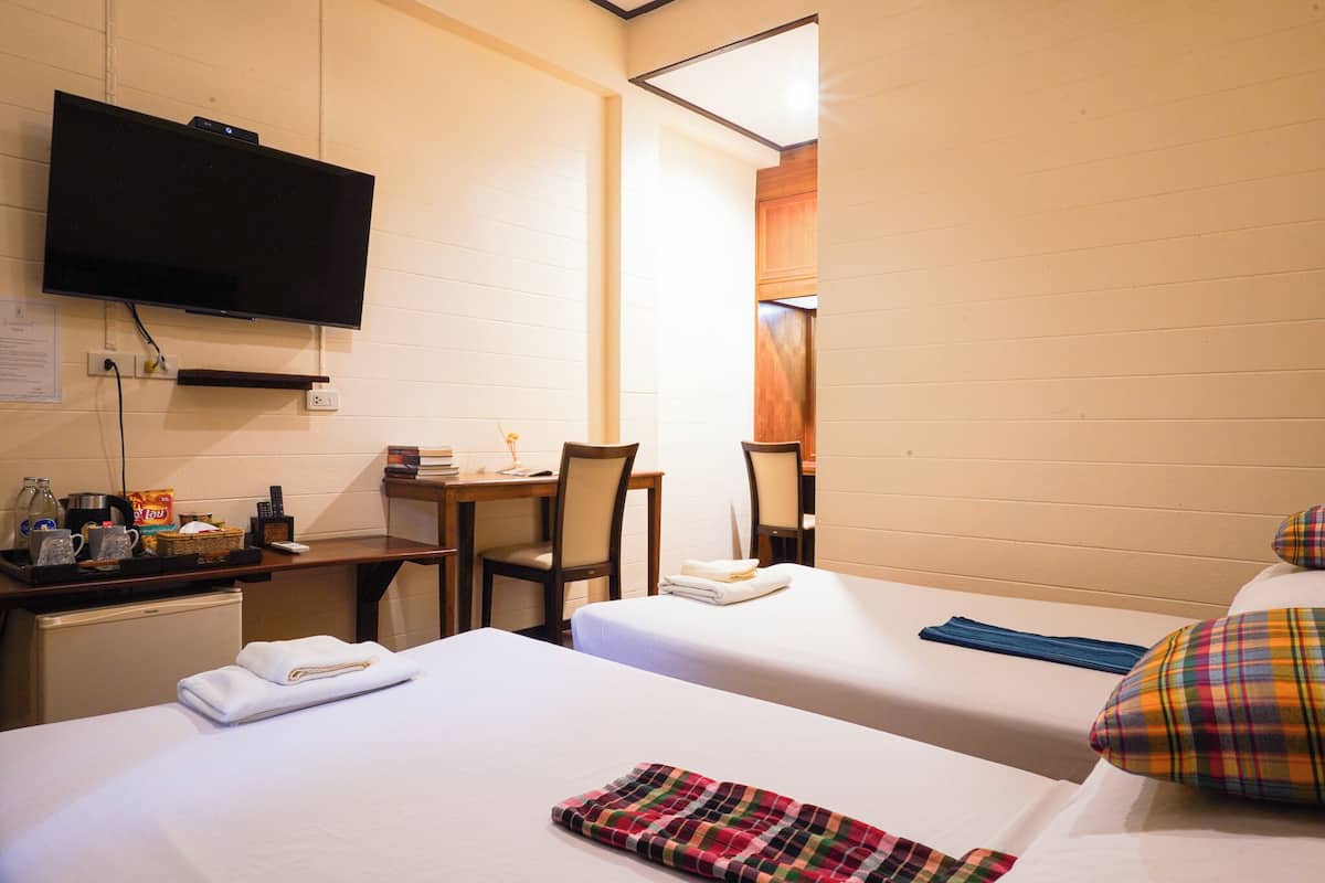 Quarto de hotel com duas camas, uma mesa de escritório com computador, televisão e uma pequena cozinha equipada.