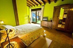 Quarto com cama, guarda-roupa de madeira e porta de vidro deslizante para uma varanda.