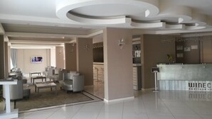 Um lobby moderno de hotel com uma receção, área de estar e bar.