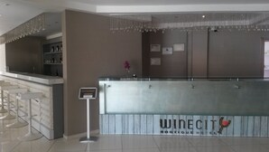 Uma área de recepção com bar, um aviso indicando ser um restaurante e um letreiro para um hotel boutique de vinhos.