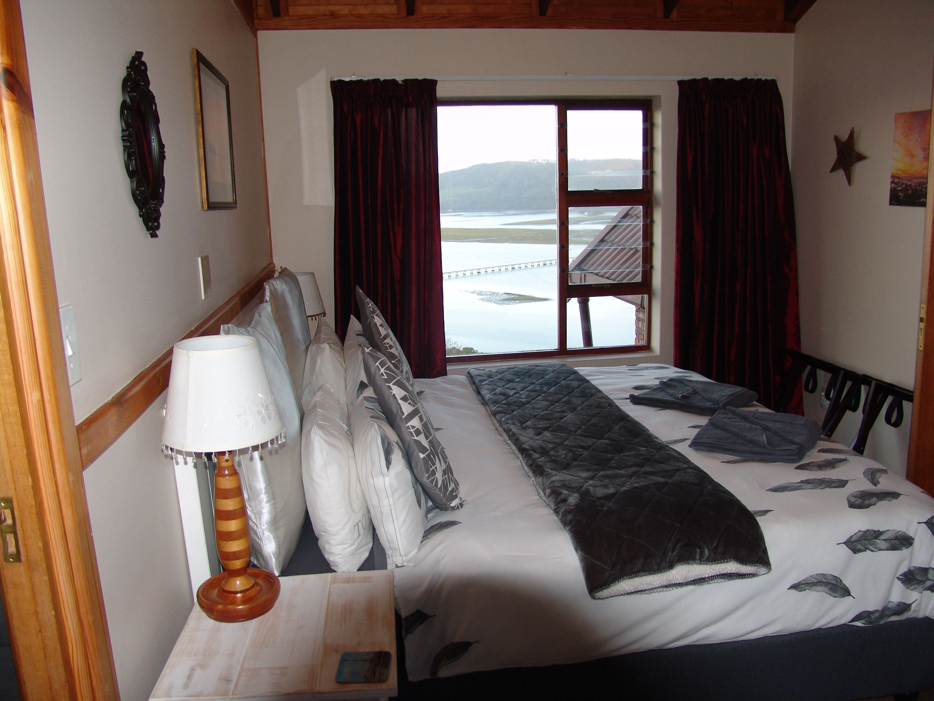 Quarto com cama, abajur, vista para um corpo de água e decoração com estrelas na parede.