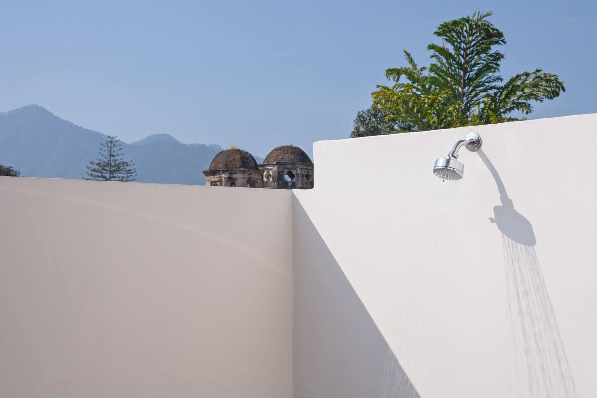Chuveiro moderno com vista para uma cordilheira e um edifício com estruturas em cúpula ao fundo.