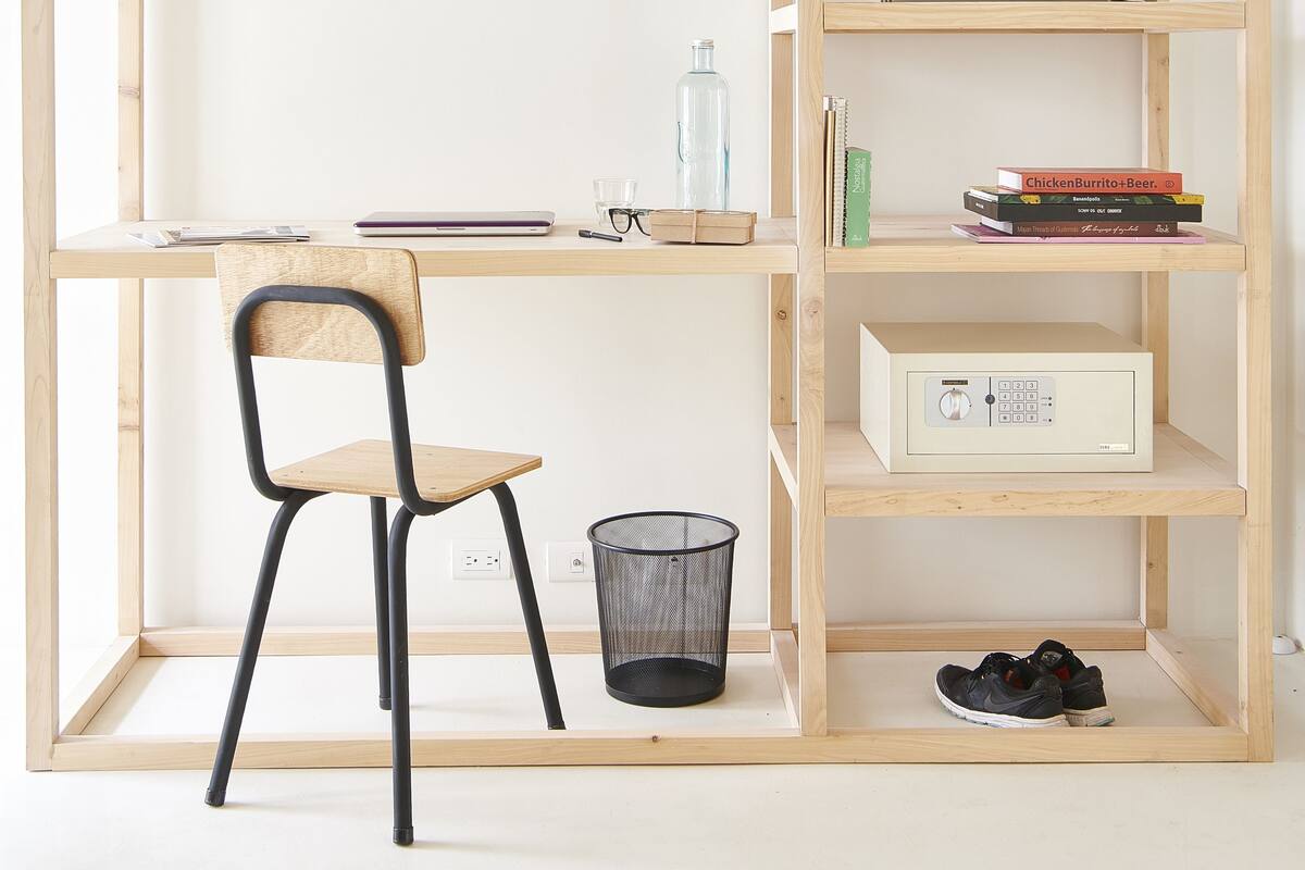 Um espaço de trabalho minimalista com mesa de madeira, cadeira e estante.