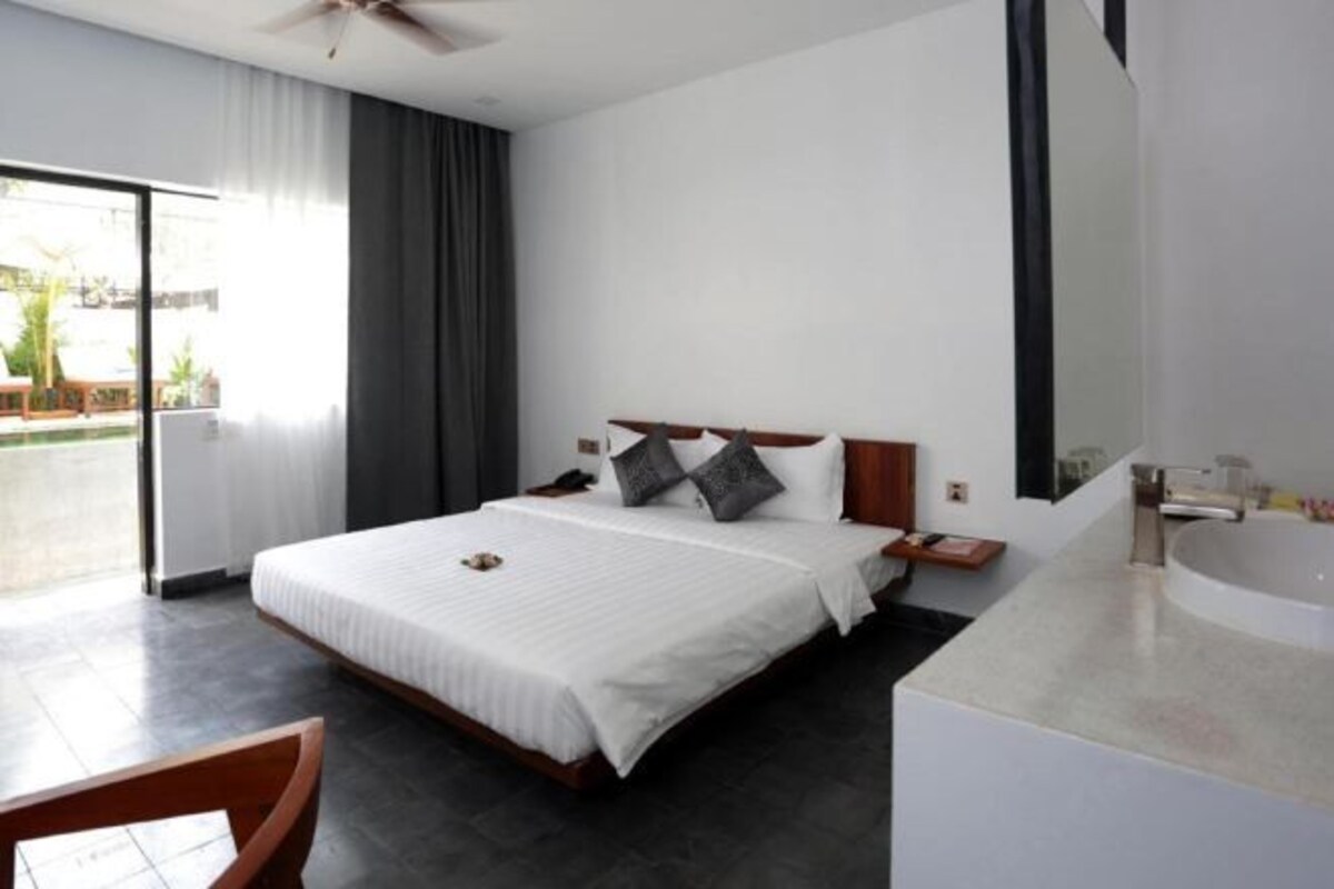 Quarto de hotel moderno com uma cama grande, banheiro com banheira e porta de vidro deslizante para o exterior.