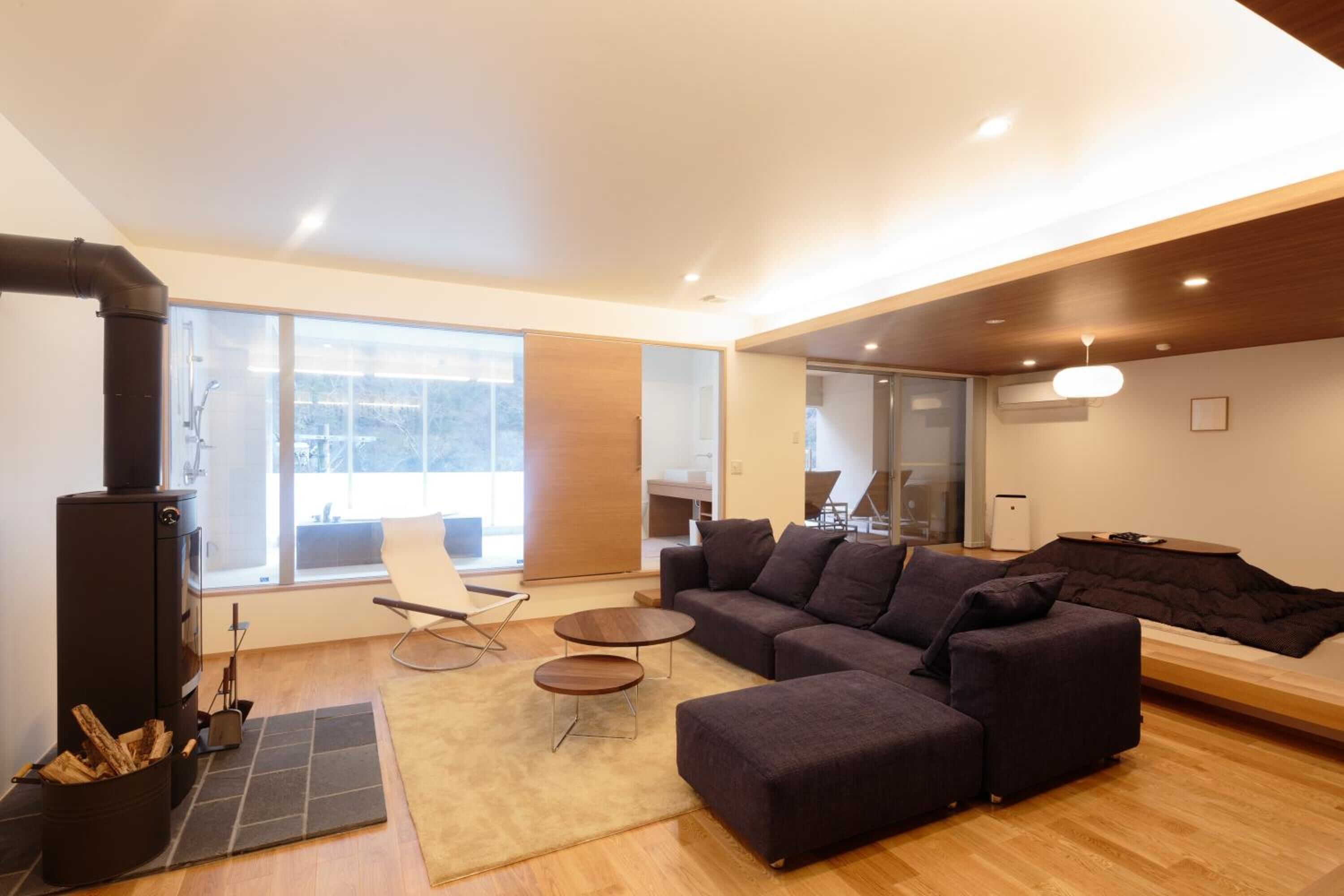Uma sala de estar moderna com sofá modular, lareira e uma grande janela com vista para o exterior.