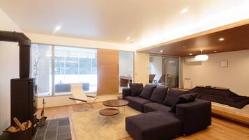 Uma sala de estar moderna com sofá modular, lareira e uma grande janela com vista para o exterior.