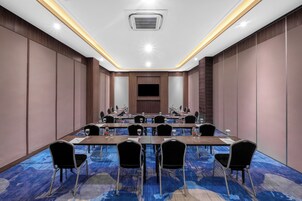 Uma sala de conferências com uma mesa comprida, cadeiras e uma televisão de tela plana.