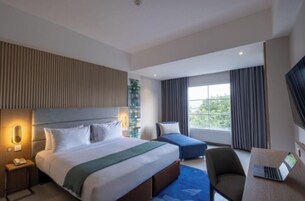 Quarto de hotel moderno com uma cama grande, uma escrivaninha e um laptop.