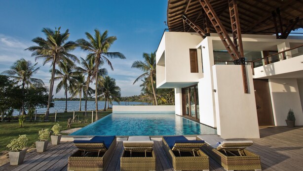 Um resort moderno com piscina, espreguiçadeiras e vista para o oceano.