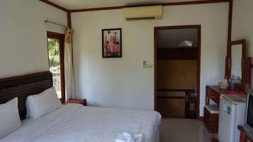 Quarto de hotel com cama, escrivaninha, espelho e televisão.