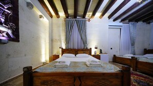 Uma cama de madeira com colcha estampada, uma mesa de cabeceira com abajur e uma janela com cortinas.