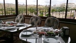 Mesa de jantar posta para quatro pessoas, com vista para colinas rochosas.