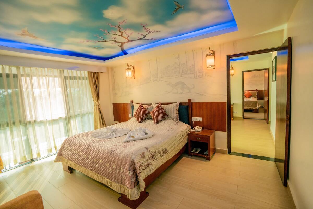 Quarto de hotel com cama, mesa de cabeceira e um espelho grande.