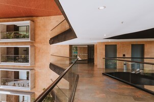 Interior moderno com vários andares, guarda-corpos de vidro e uma combinação de iluminação natural e artificial.