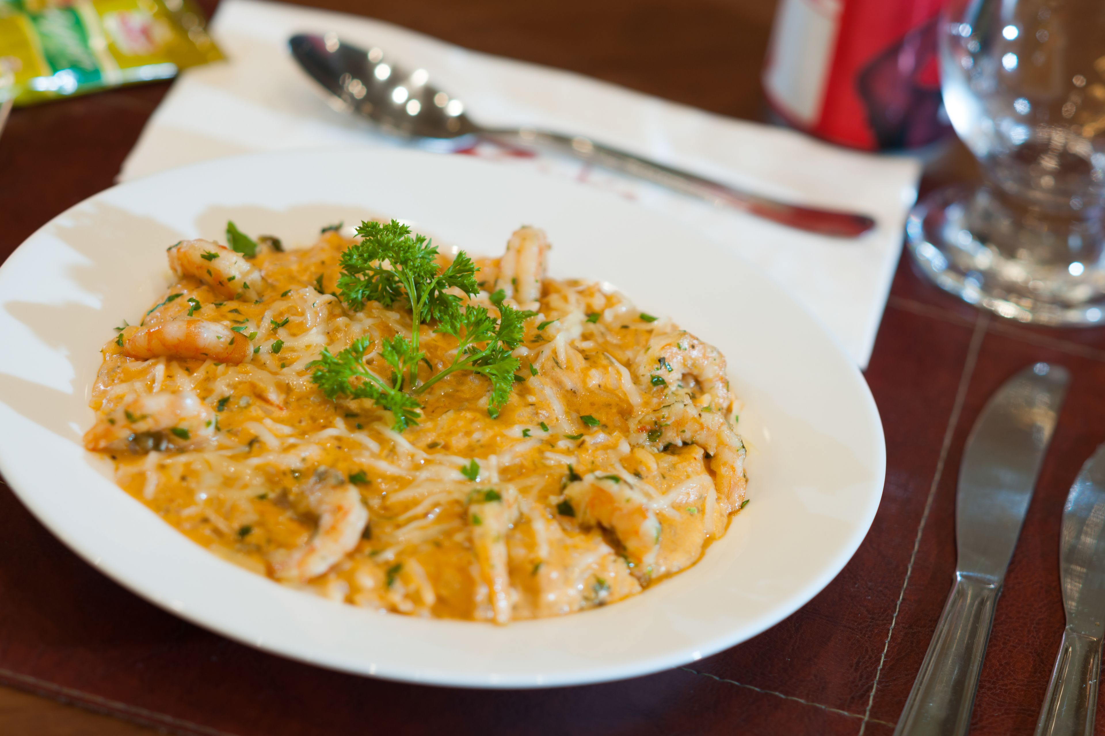 Um prato de massa com molho cremoso, decorado com salsa, sobre um prato branco.