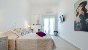 Quarto com cama, mesa de cabeceira, cômoda, espelho, televisão e um quadro na parede.