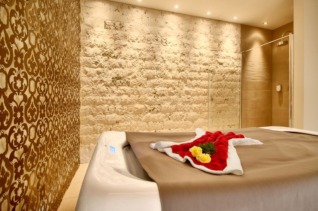 Uma sala de spa com parede de pedra, mesa de massagem e área de chuveiro.