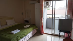 Quarto de hotel com cama, escrivaninha, cadeira e vista para o exterior.
