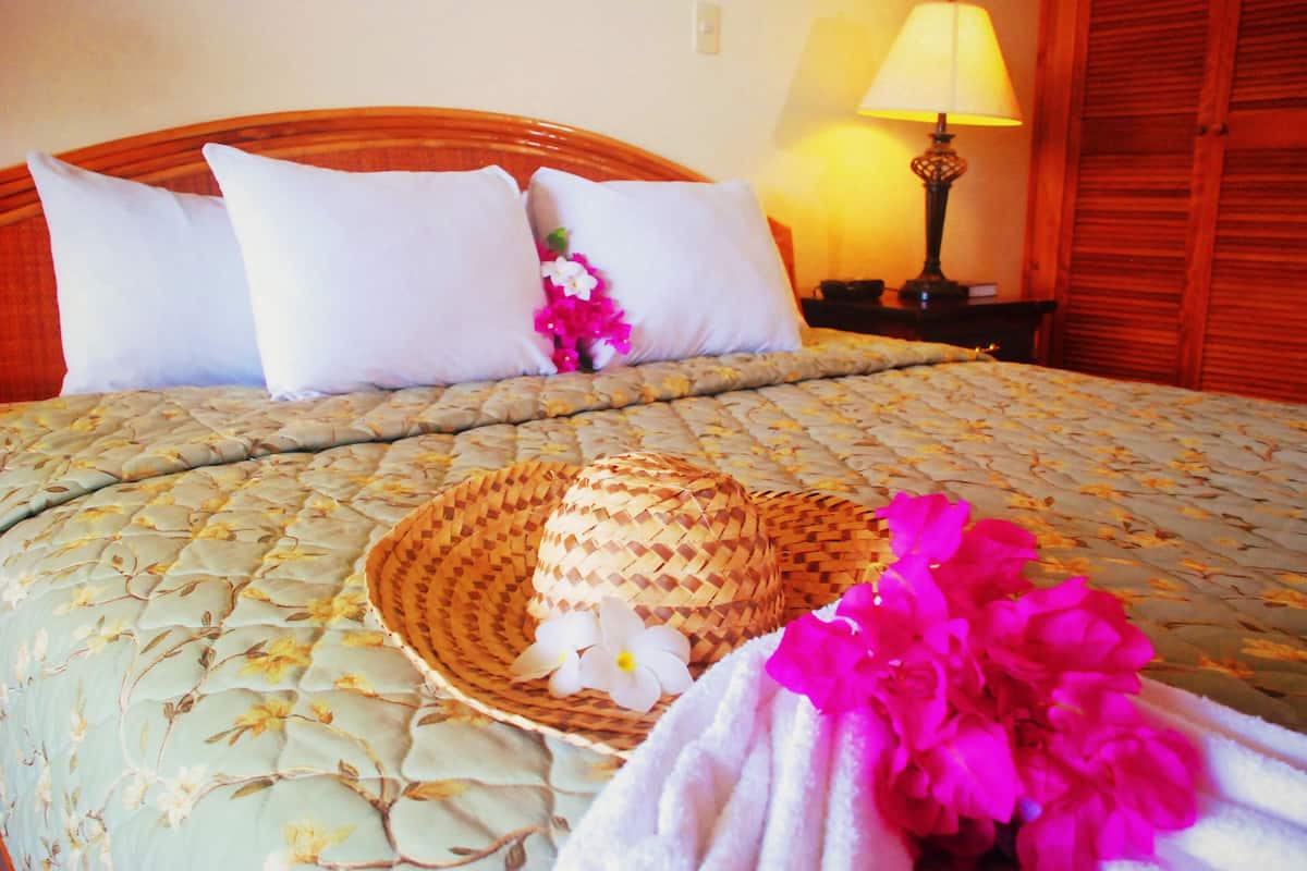 Uma cama bem arrumada com um espalhadeira floral, um chapéu de palha e um buquê de flores.
