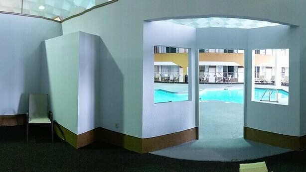 Um saguão de hotel com vista para a piscina, um espaço de estar e uma área de recreação infantil.