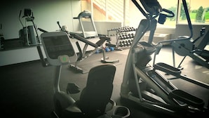 Uma academia com diversos equipamentos de exercícios, incluindo esteira, elíptico e pesos.