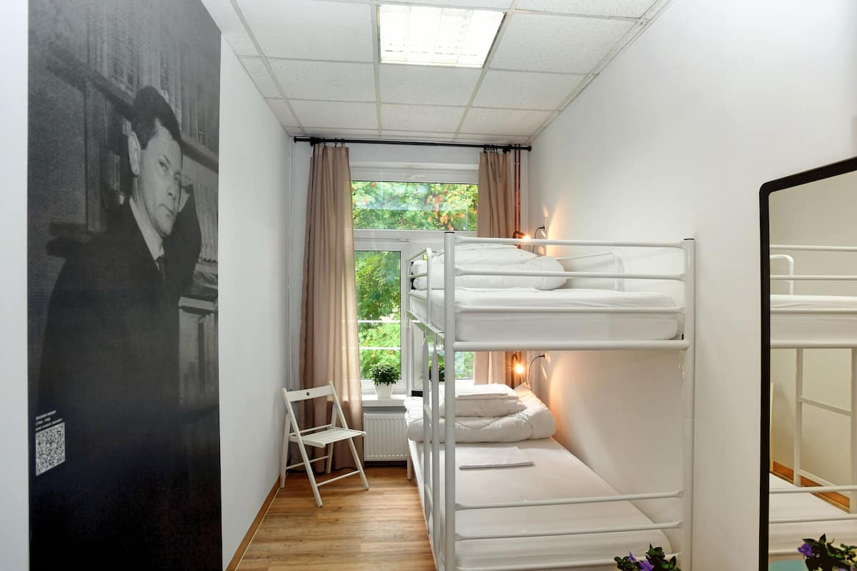 Quarto com beliche, janela, cadeira e um cartaz na parede.