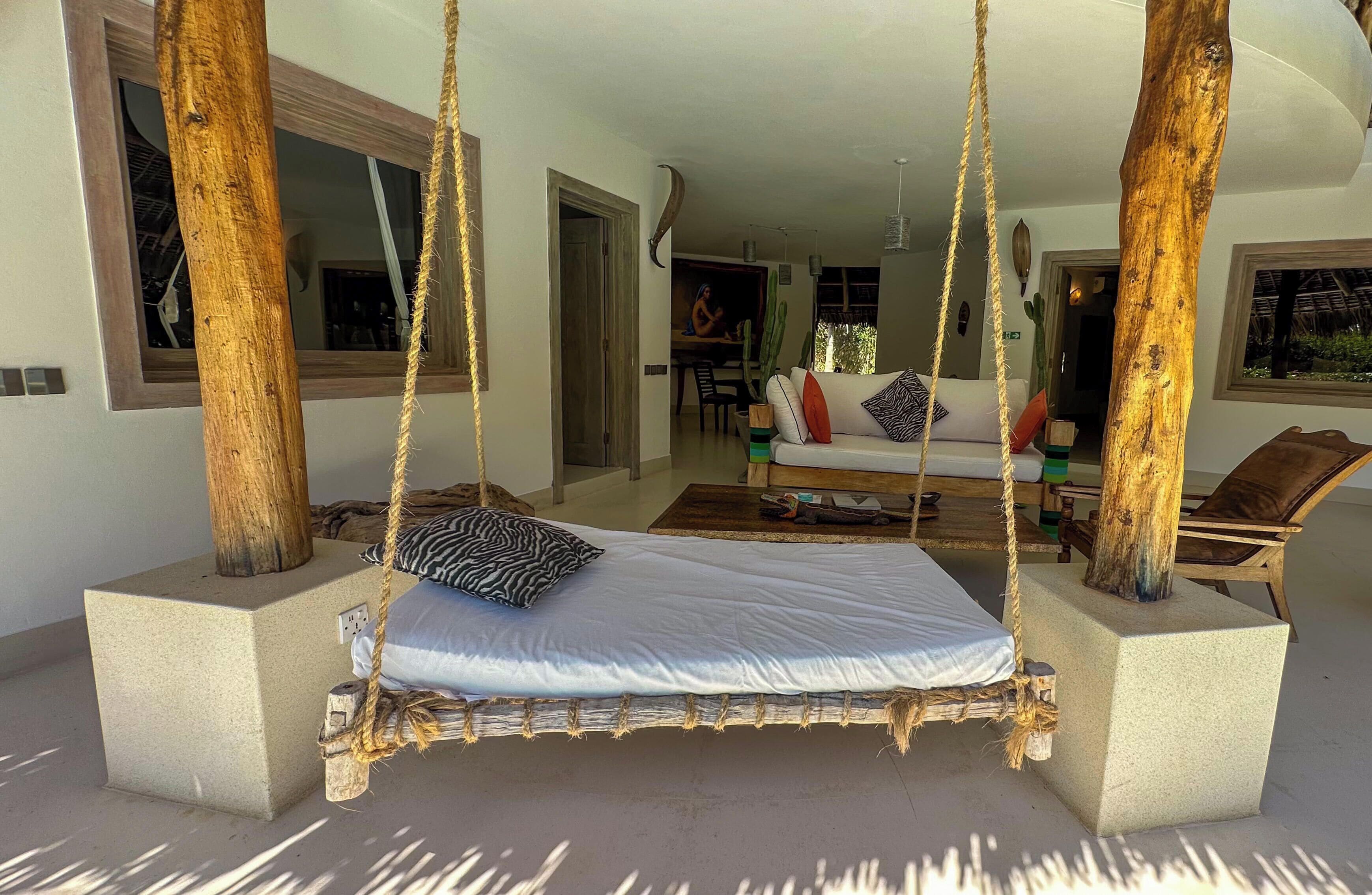 Quarto com rede suspensa, área de jantar e vista para o exterior.