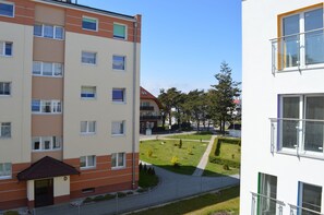 Um edifício residencial de vários andares com telhado plano, várias janelas e uma pequena área de jardim com caminhos.