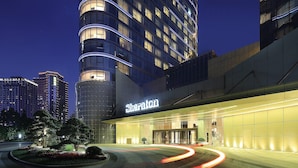 Um hotel Sheraton com fachada moderna, grandes janelas e entrada bem iluminada.