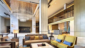 Um hall amplo com um grande candelabro, assentos confortáveis e uma área de recepção.