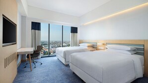 Quarto de hotel com duas camas, uma escrivaninha e uma cadeira.