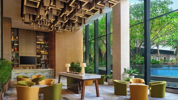 Um lobby moderno com área de bar, assentos e grandes janelas com vista para uma piscina.