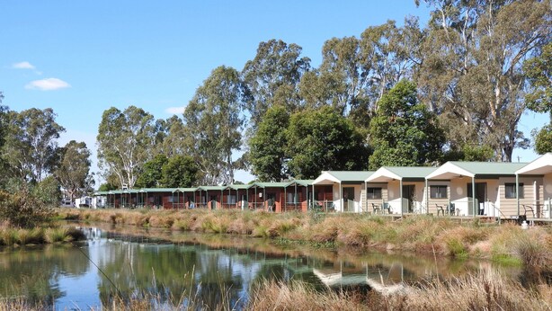Uma fileira de cabanas com um lago ao primeiro plano.