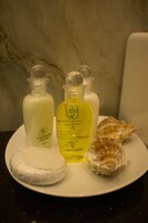 Um prato branco com três frascos de líquido de banho e um sabonete branco.
