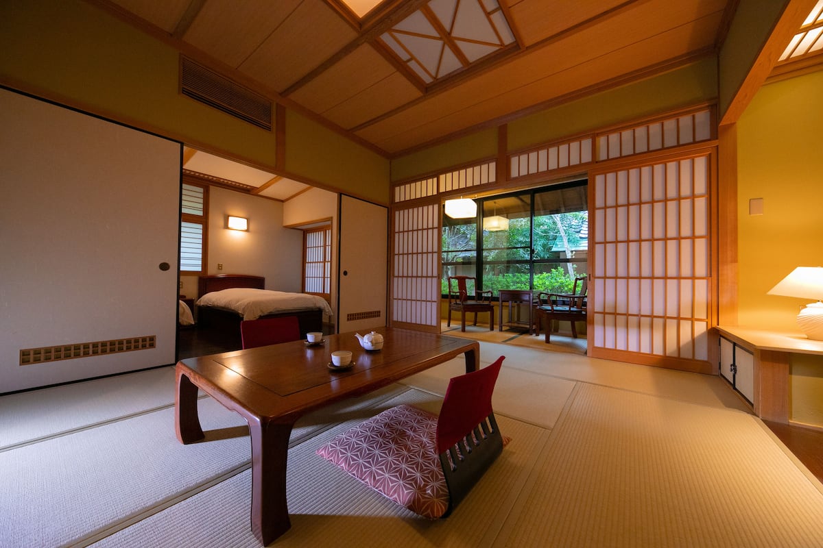Um quarto japonês tradicional com tatames, uma mesa de madeira baixa e um futon.