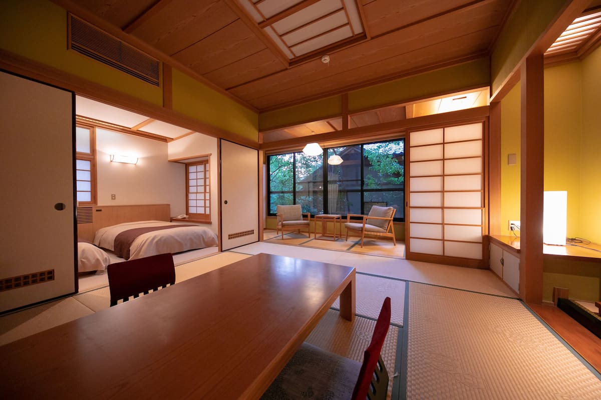 Quarto japonês tradicional com tatames, uma mesa de madeira baixa e uma cama futon.