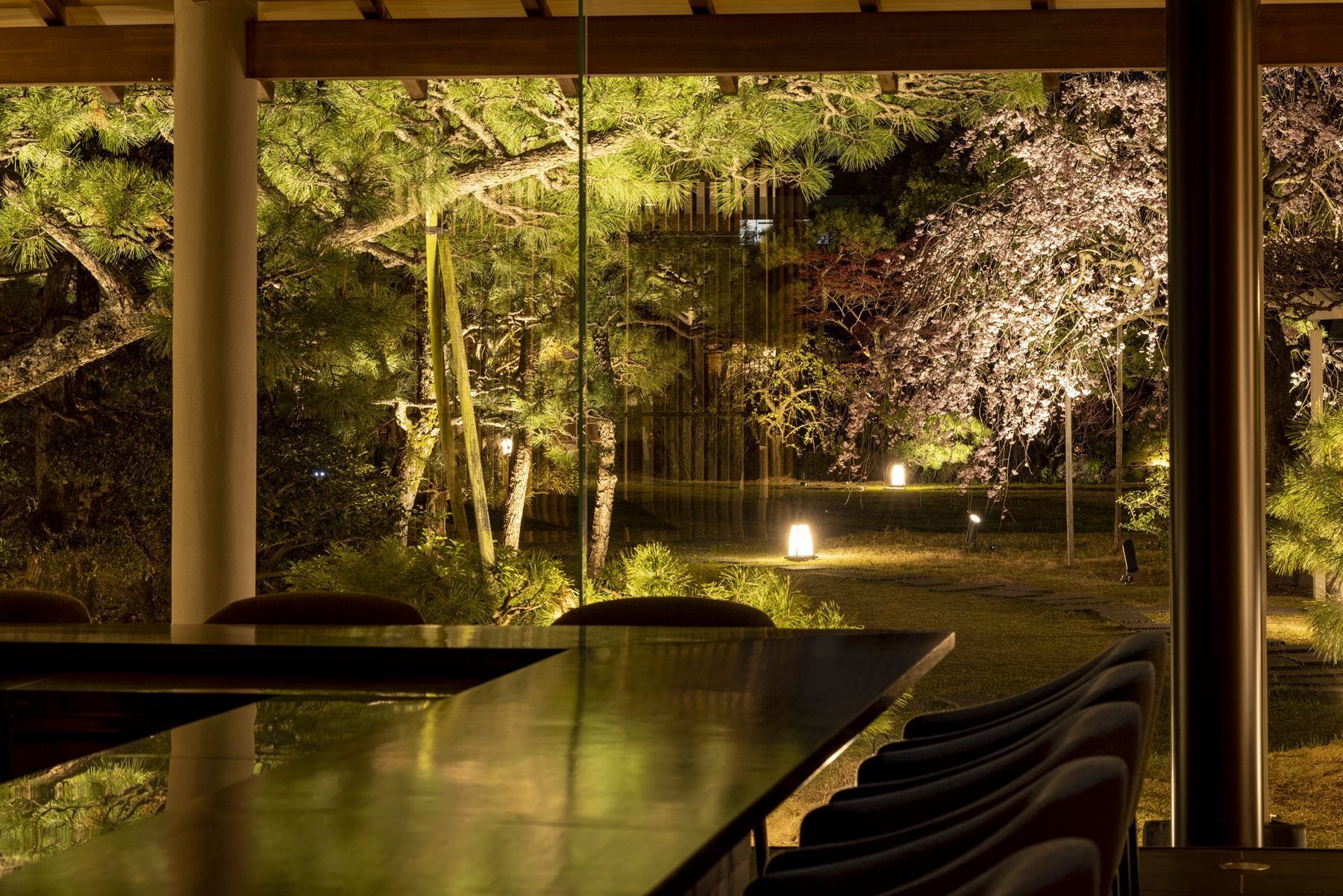 Uma área de refeições com vista para um jardim à noite.