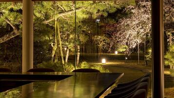 Uma área de refeições com vista para um jardim à noite.