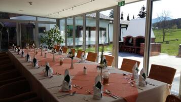 Um restaurante com mesas ao ar livre, grandes janelas e vista para o exterior.