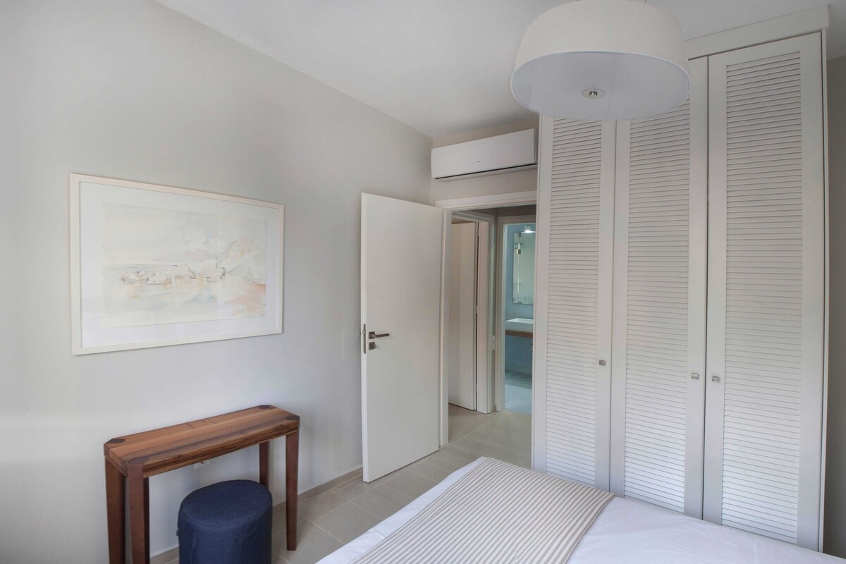 Quarto com cama, mesa de cabeceira, cadeira, guarda-roupa e um quadro na parede.