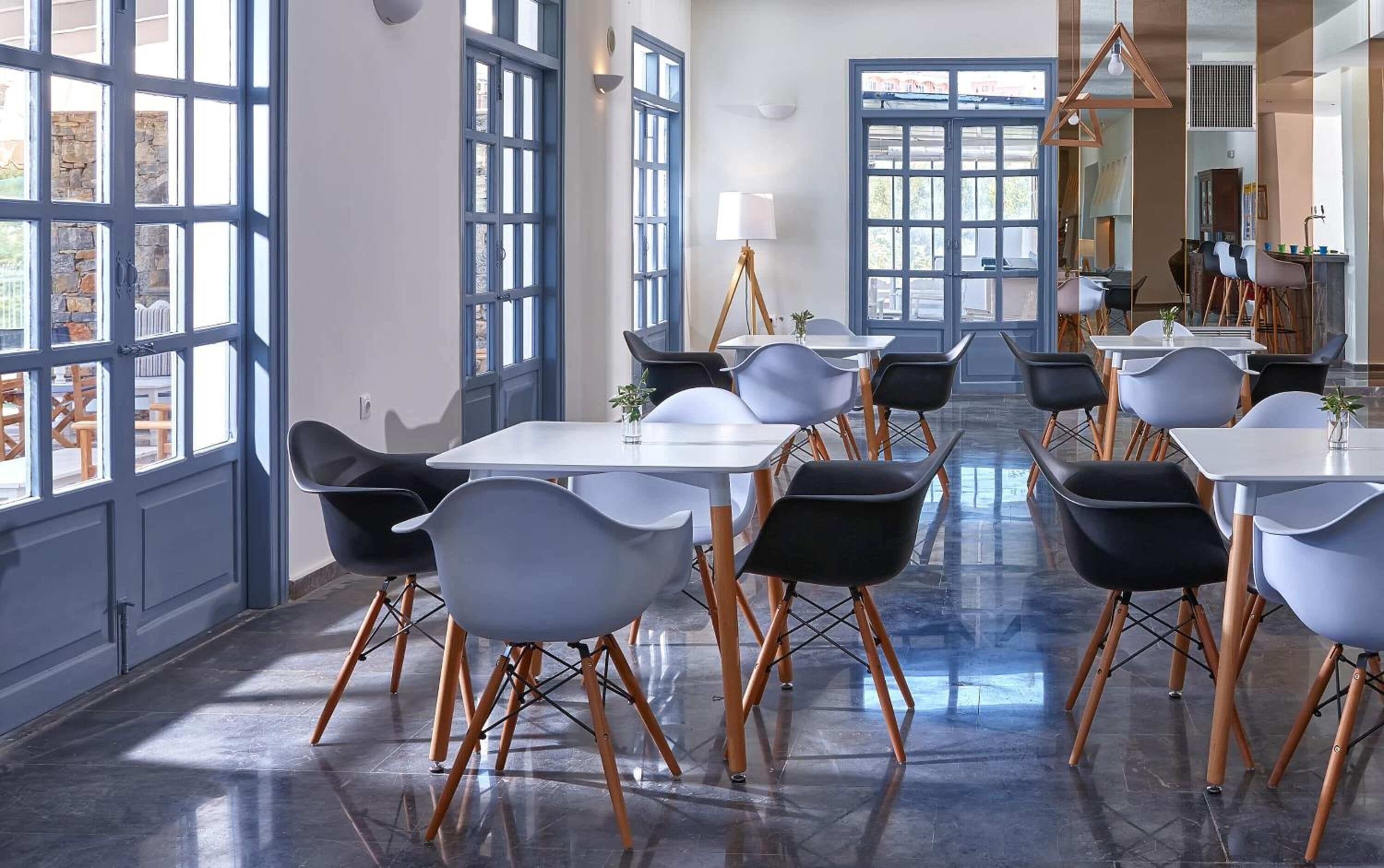 Uma área de refeições moderna com mesas, cadeiras, janelas amplas e vista para o exterior.