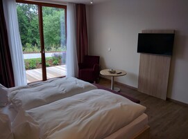Quarto de hotel com duas camas, uma televisão, uma mesinha e uma cadeira.