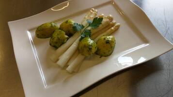 Prato com batatas assadas e aspargos em um prato branco.