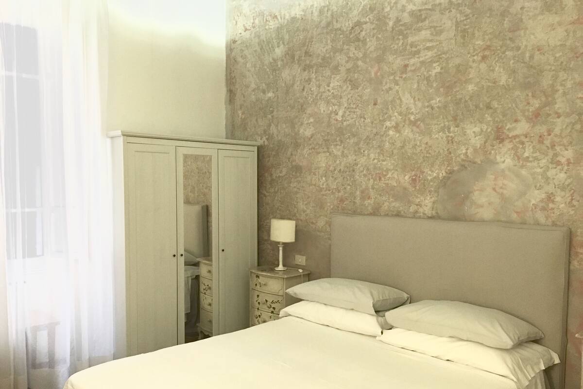 Quarto com cama, guarda-roupa, mesa de cabeceira e abajur.